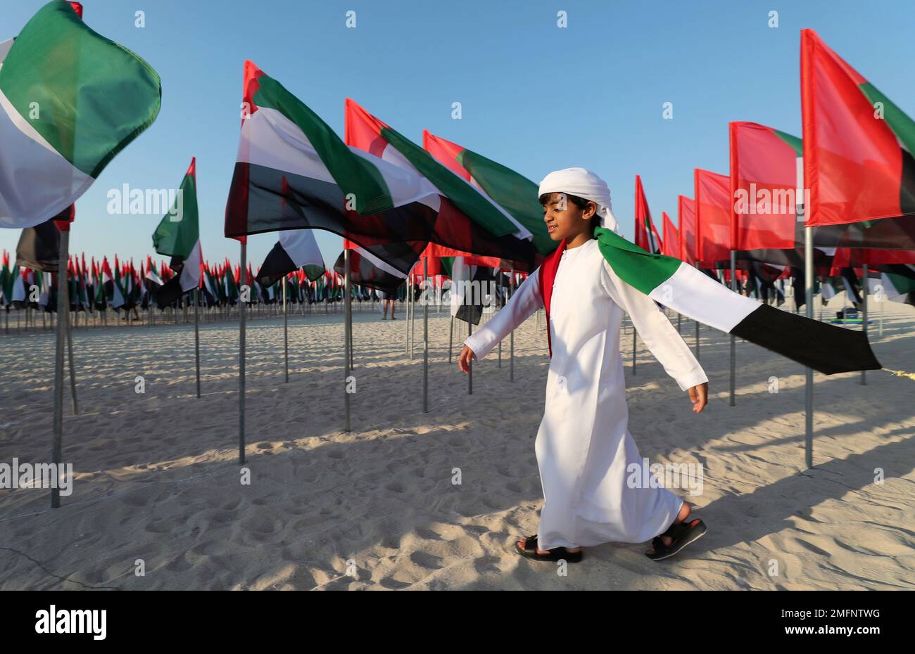 An Emirati boy walks among UAE national flags set up to celebrate the ...