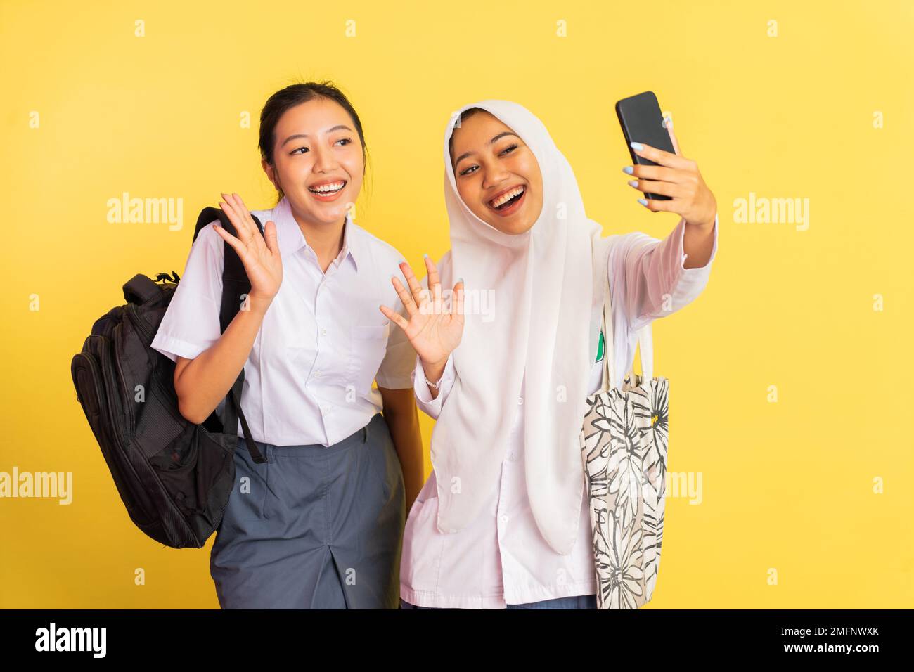 two high school girls waving during video call using handphone Stock ...