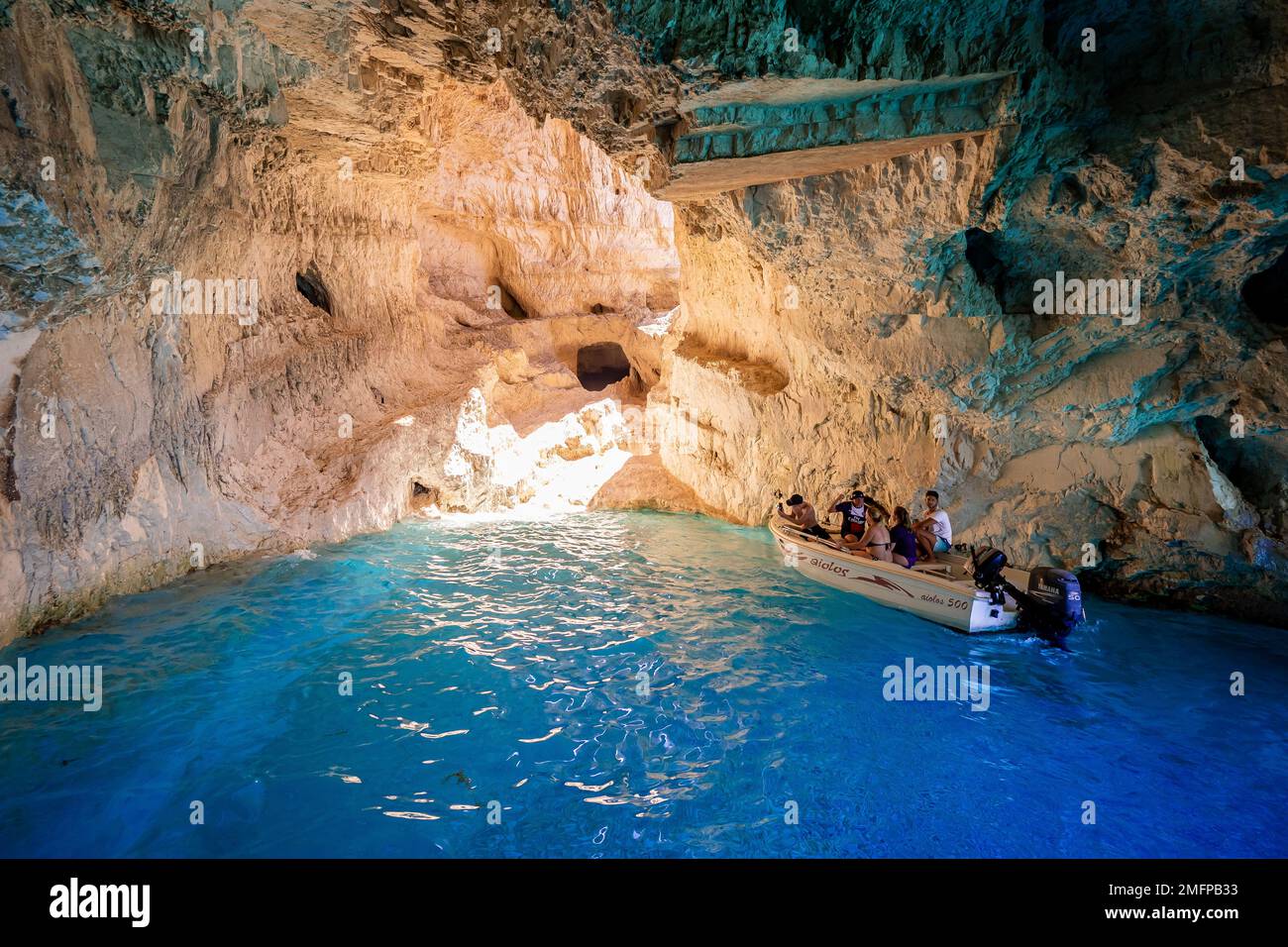 Tourists on an excursion boat explore the inside of a sea grotto ...