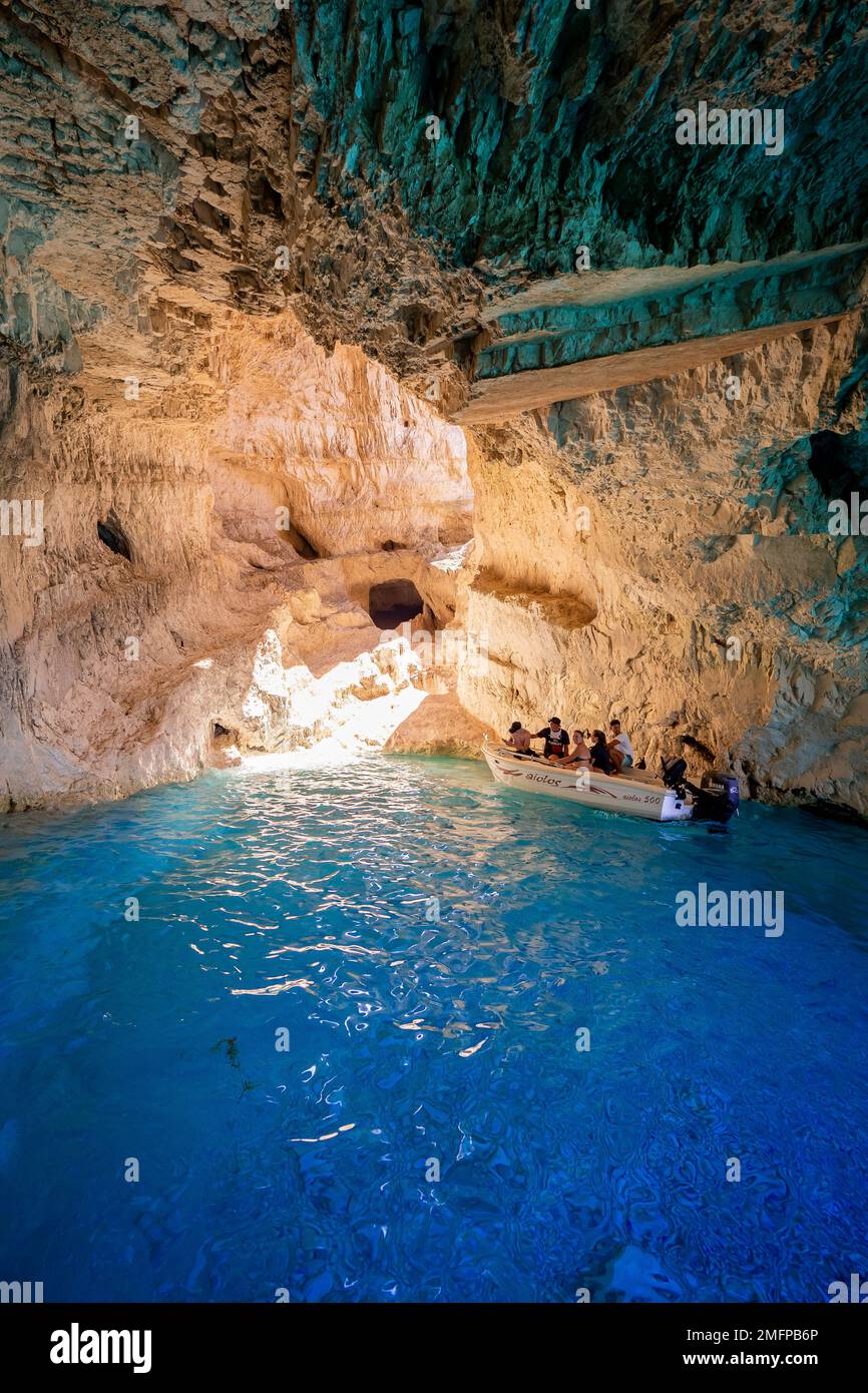 Tourists on an excursion boat explore the inside of a sea grotto ...
