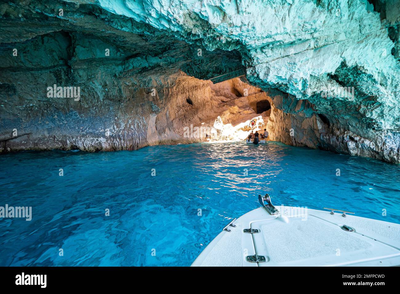 Tourists on an excursion boat explore the inside of a sea grotto ...