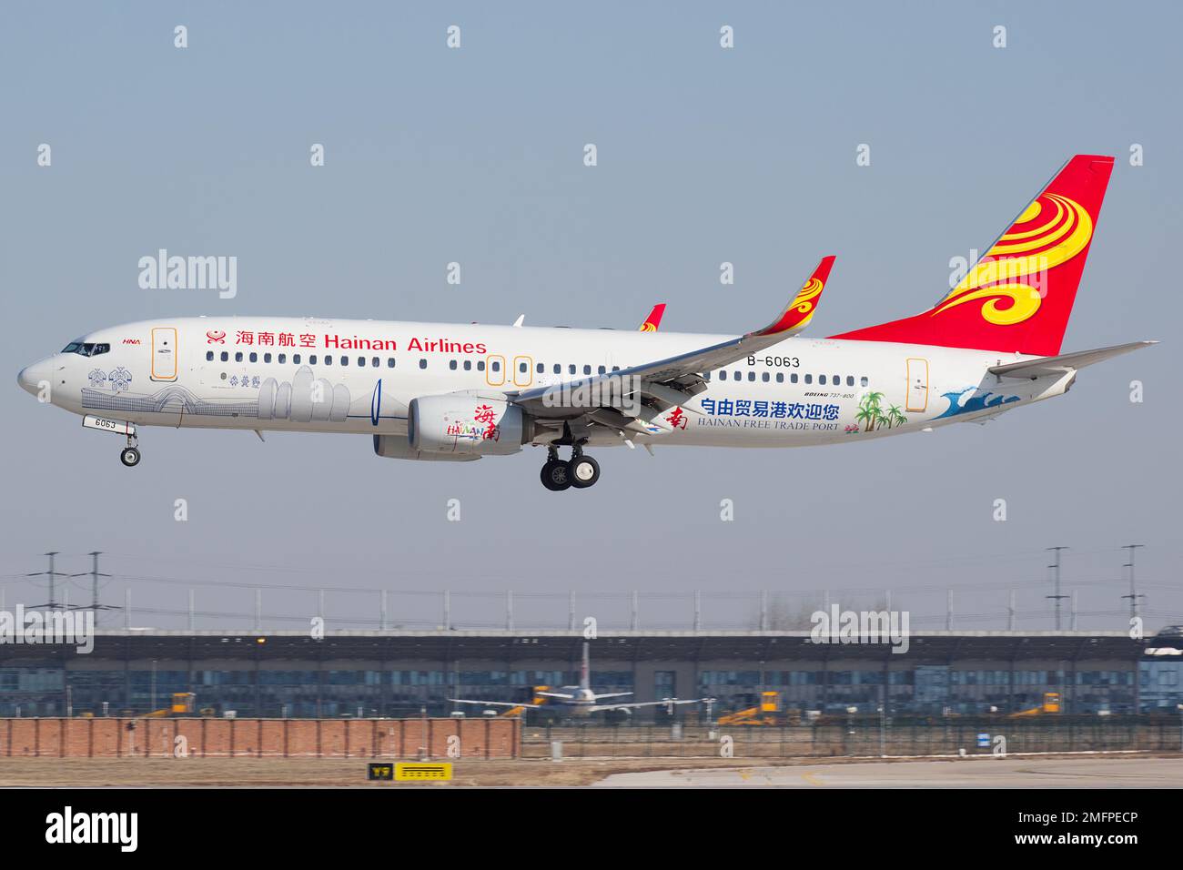 An airplane landing on a runway against a blue sky in Tianjin, China ...