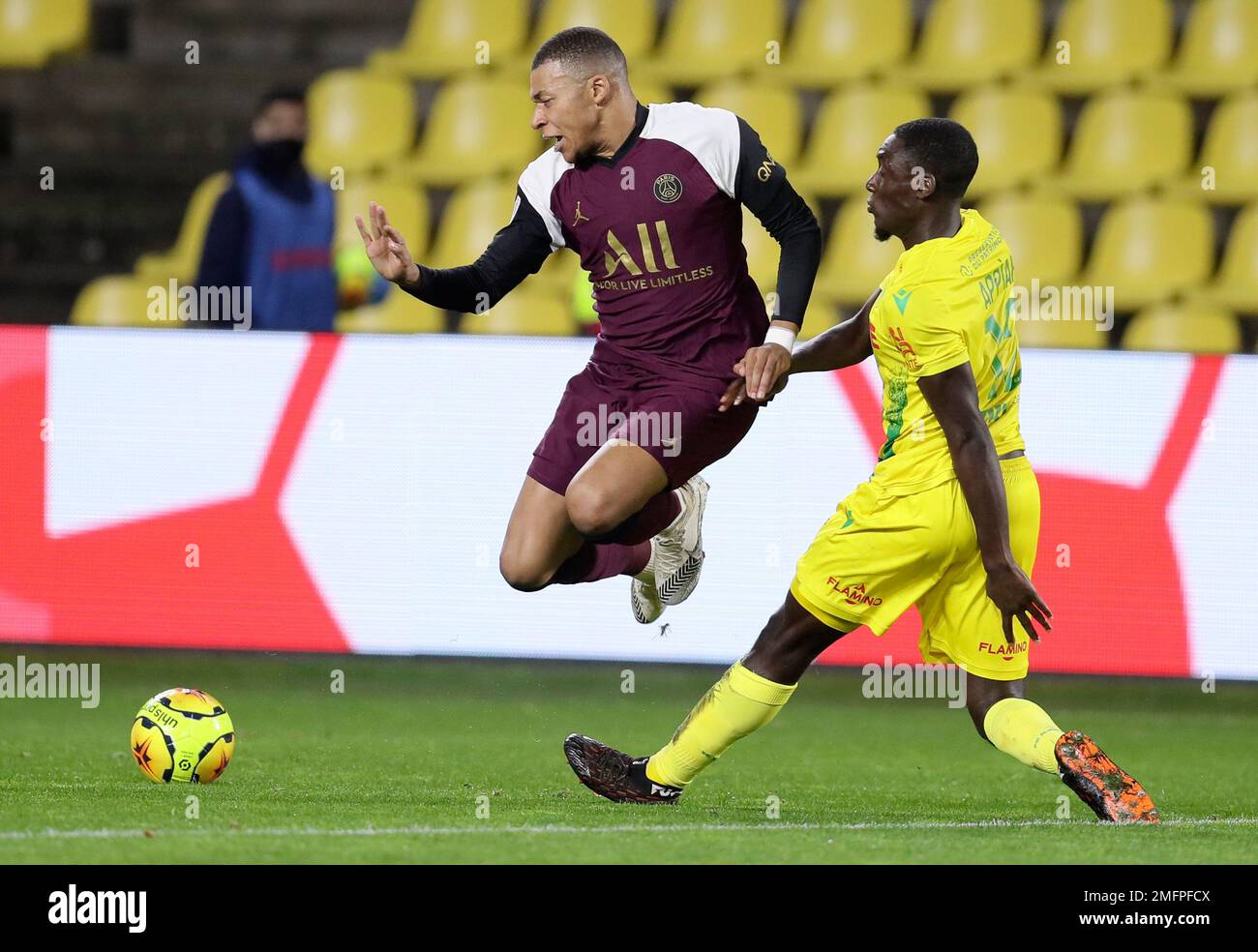 PSG's Kylian Mbappe, left, jumps clear of a tackle by Nantes' Dennis ...