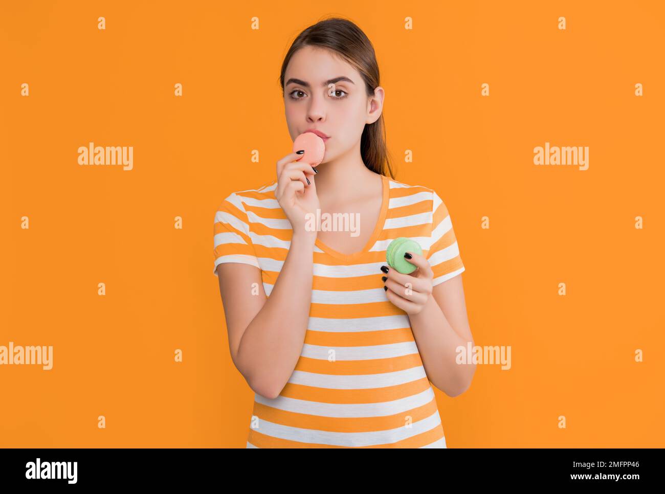young girl eating macaron on yellow background Stock Photo - Alamy