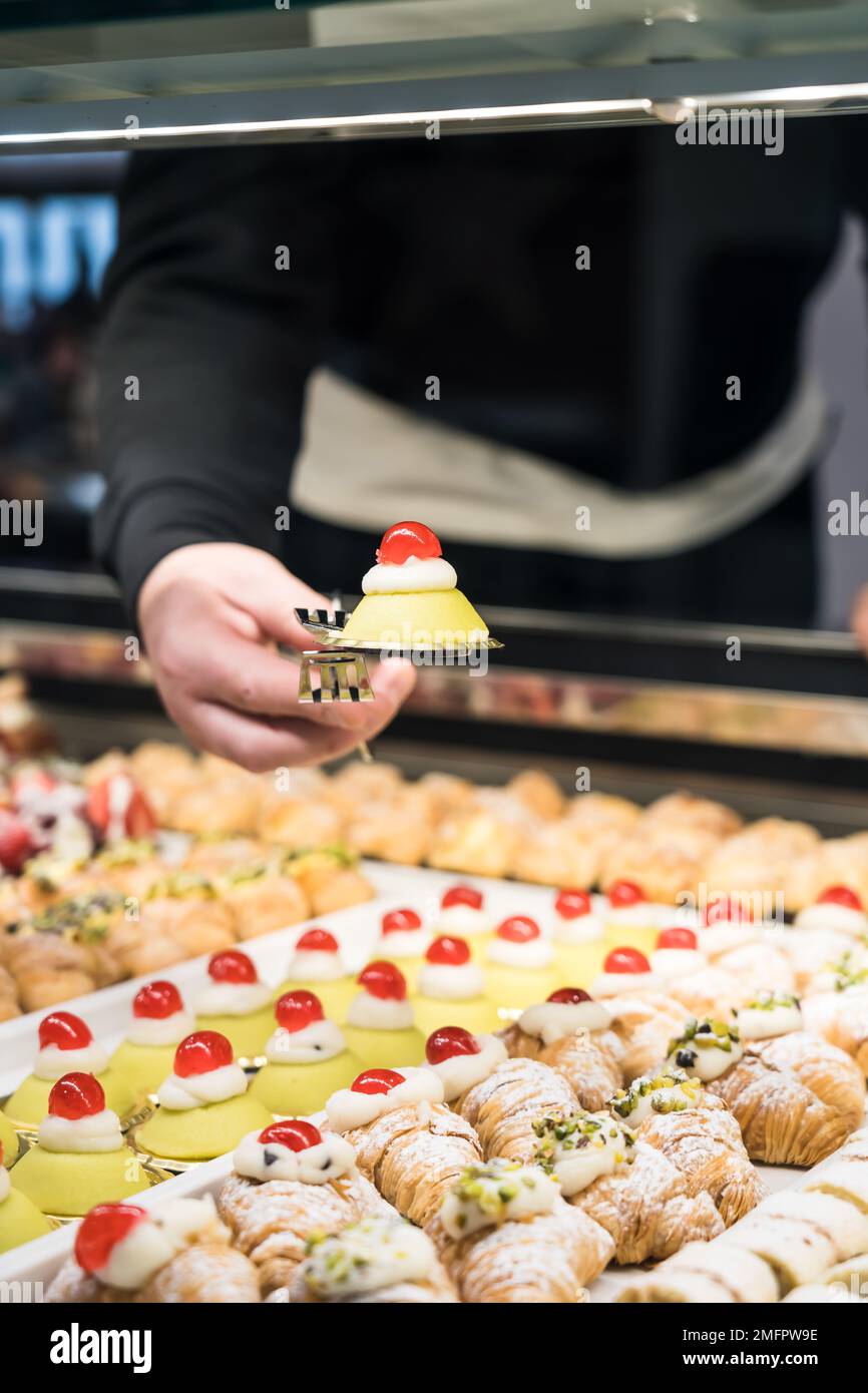 Unrecognizable baker picking up a traditional italian pastry at a ...
