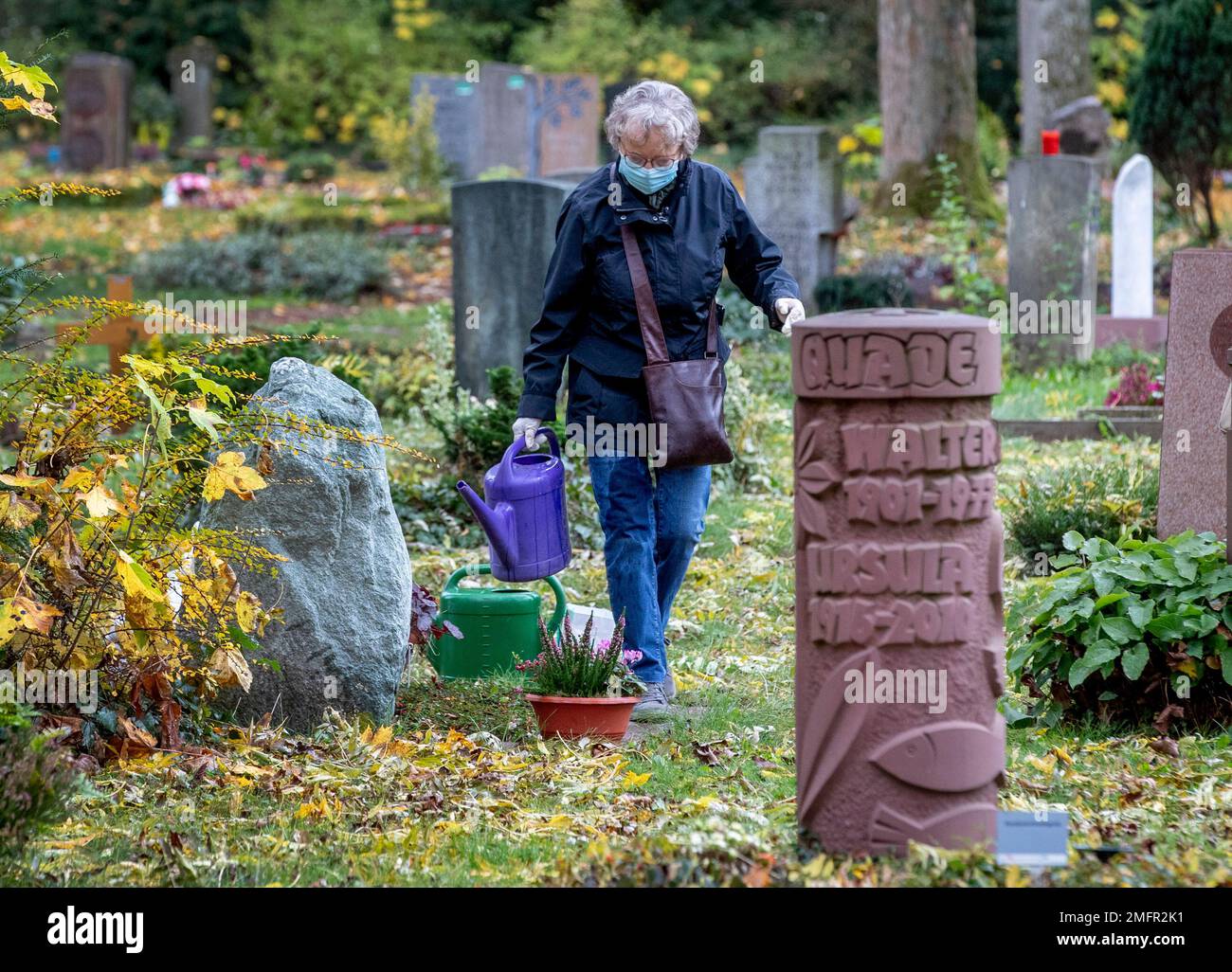 An elderly woman wearing a face mask takes care of a grave at the main ...
