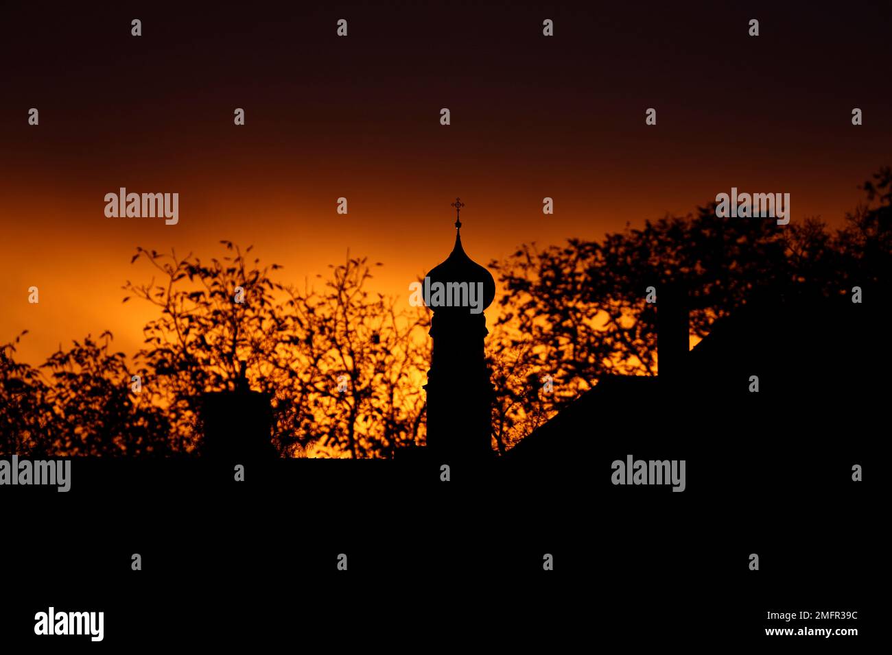 The tower of St. Theresia is silhouetted by the rising sun in Munich ...