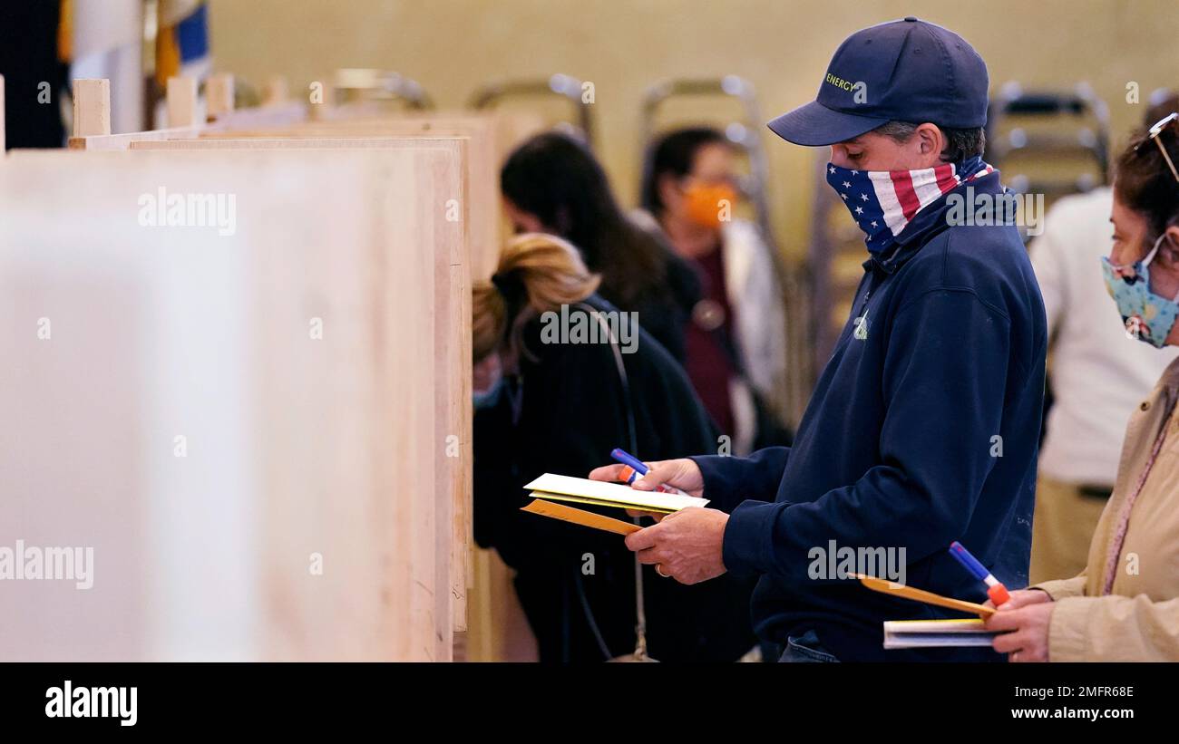 Bruce Lowell looks down at his ballot as he enters a voting booth at an ...