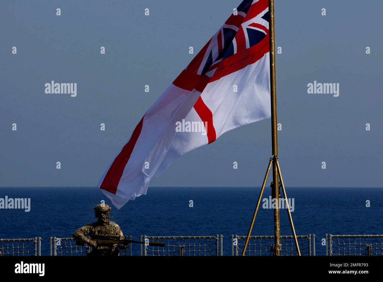 A British Royal Marine stands guards by a flag aboard the Royal Navy's ...