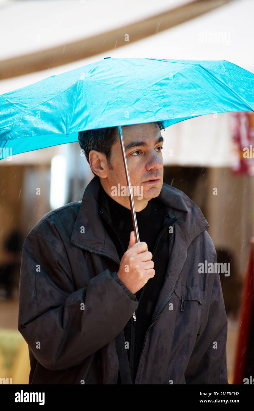 Man shelters from the rain with an umbrella Stock Photo - Alamy