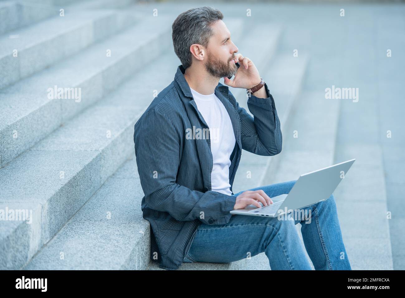 freelancing man with phone and laptop outdoor. freelancing man with ...