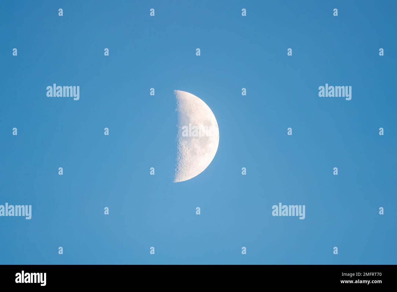 half a moon as seen from the earth with a blue background Stock Photo ...