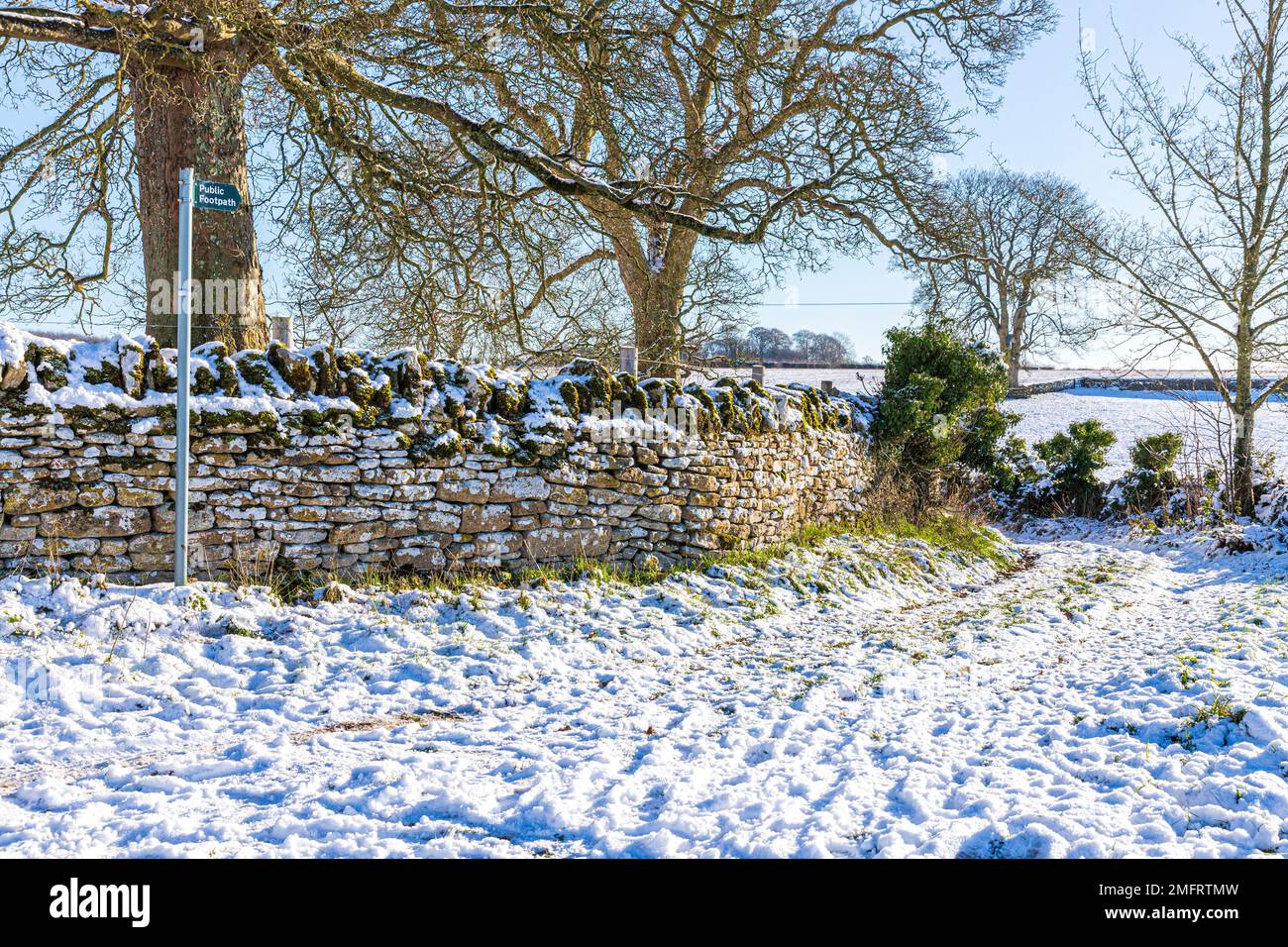A public footpath in early winter snow at the Cotswold village of ...