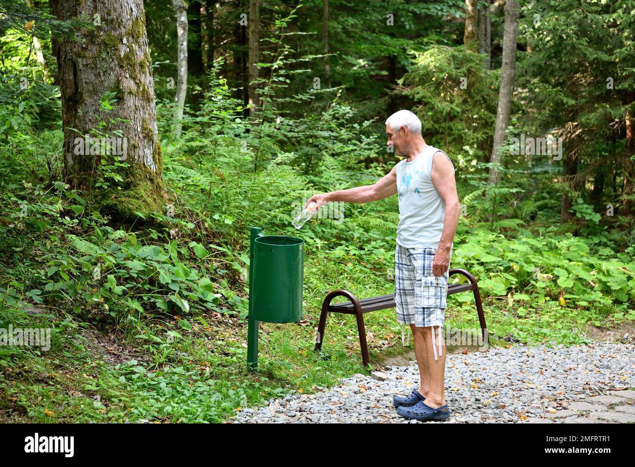 A tourist throws a plastic bottle into the trash during a walk in the ...