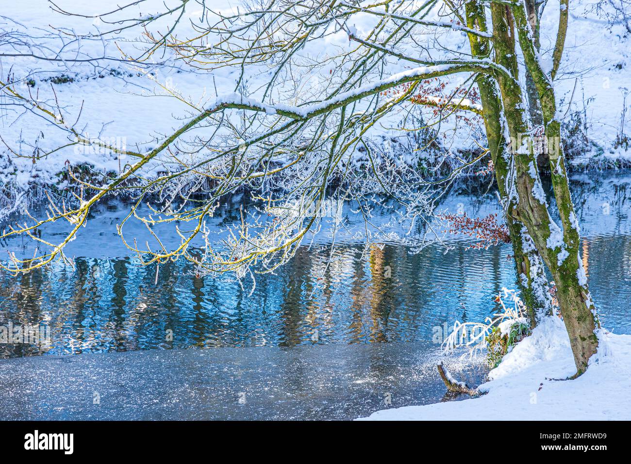 Early winter snow on the infant River Churn in the Cotswold village of ...