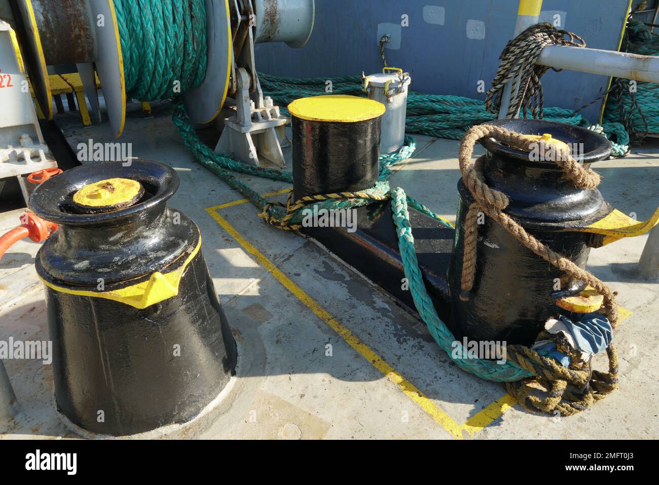 Close view on black and yellow painted bollards and mooring roller in ...