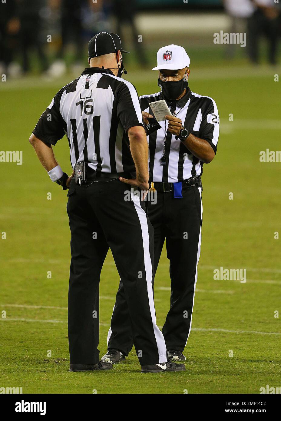 Referee Adrian Hill conferees with line judge Kevin Codey (16) during ...