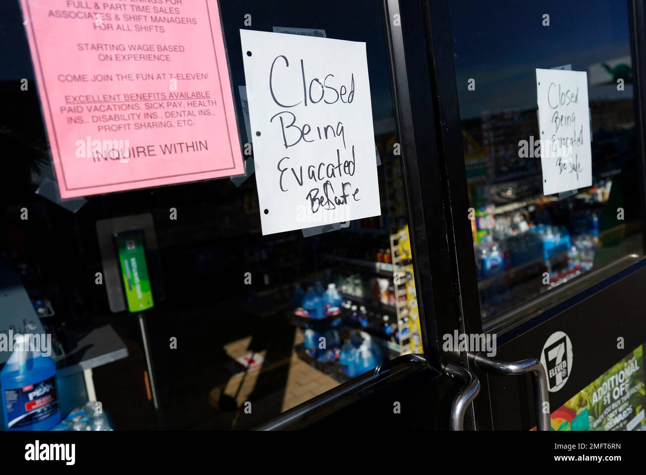 Handwritten signs hang on the doors to a closed convenience store as a ...
