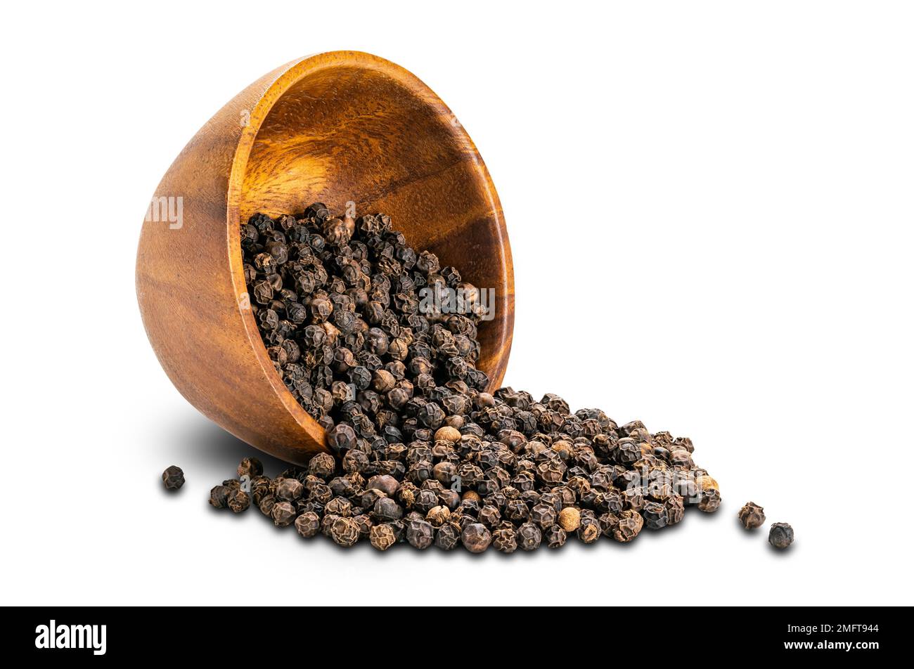 Closeup view pile of dried natural black pepper seeds in wooden cup on ...
