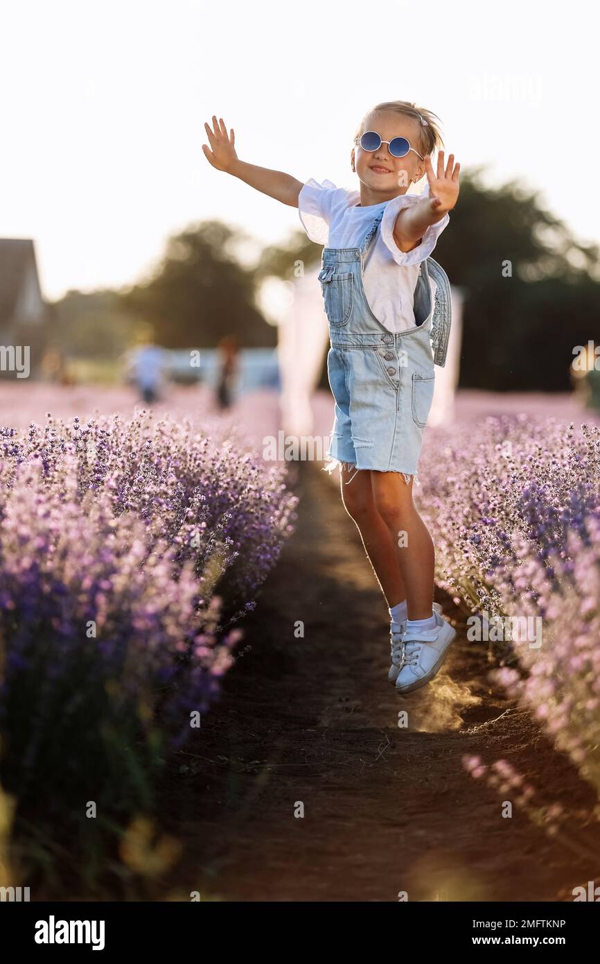 Adorable happy child girl is having fun and jumping in lavender field ...