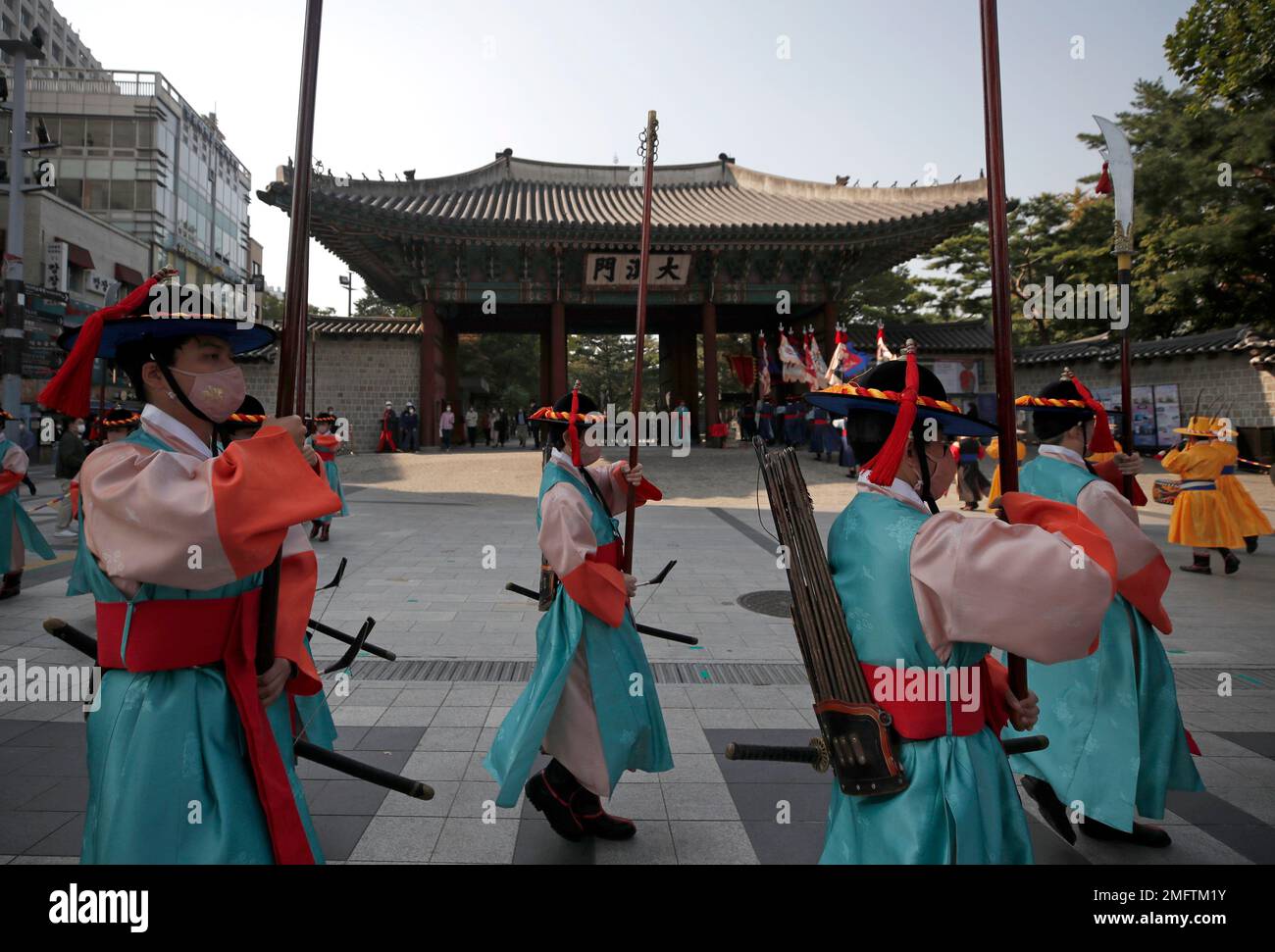 Performers wearing traditional guard uniforms and protective face masks ...