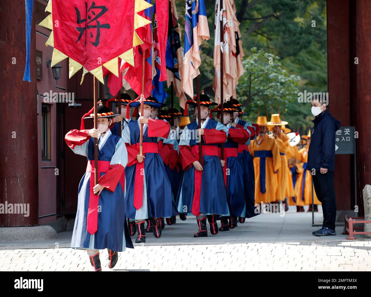 Performers wearing traditional guard uniforms and protective face masks ...