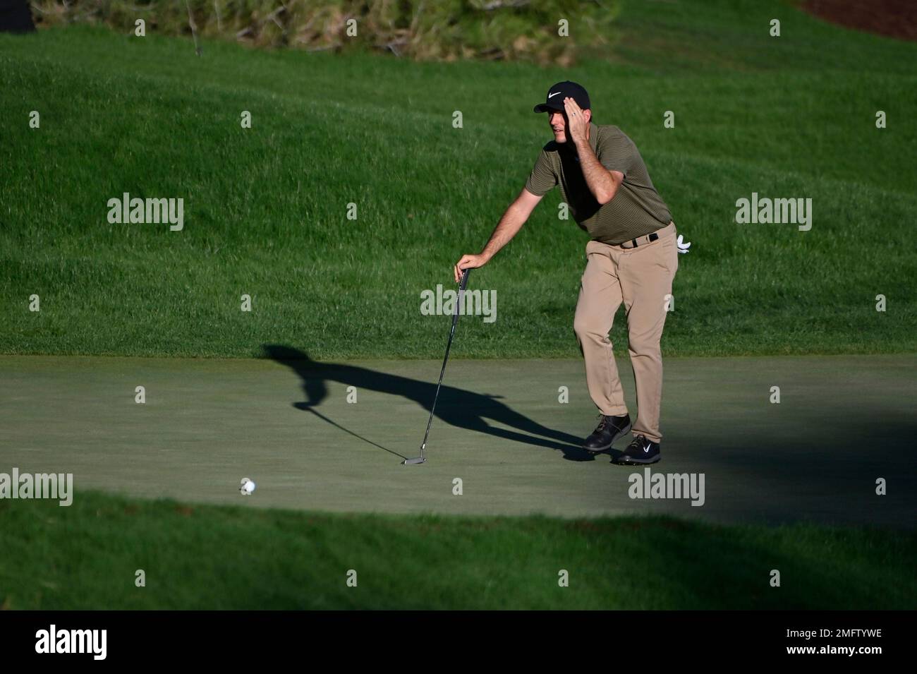 Russell Henley blocks the sun as he lines up a putt on the 18th hole ...