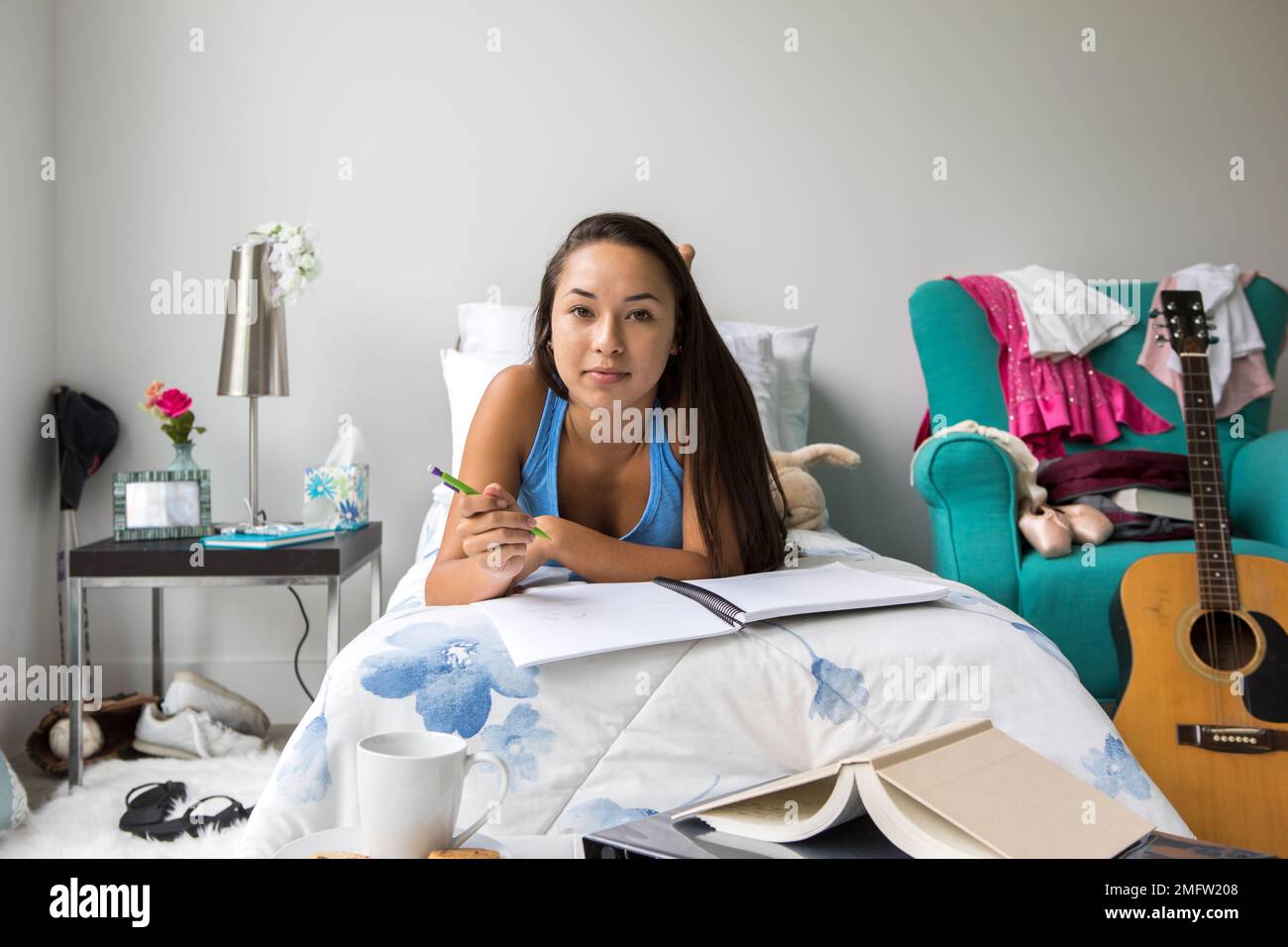 A teenage girl does homework on her bed in her bedroom Stock Photo - Alamy