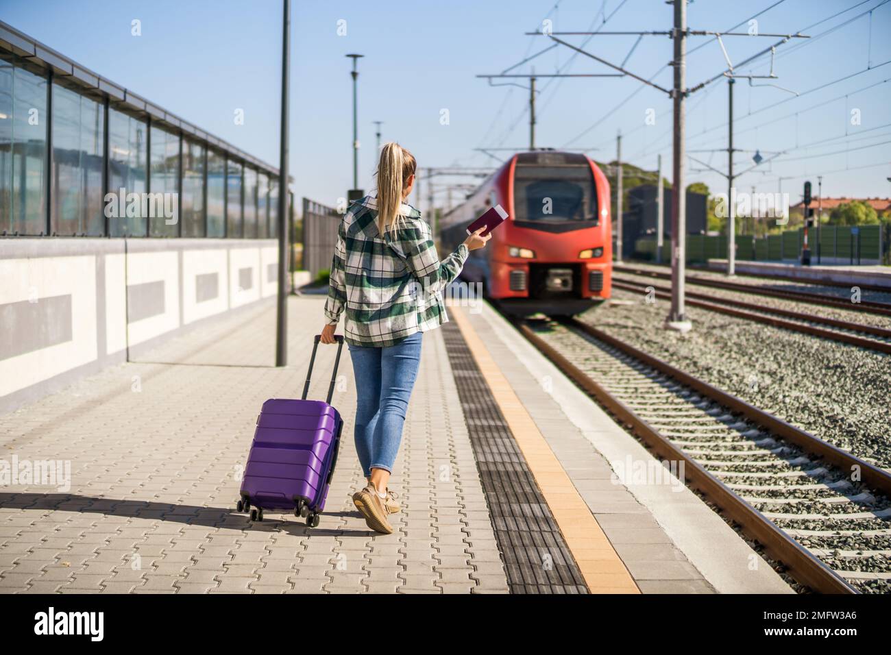 Woman with suitcase holding ticket and waiting to enter into the train ...