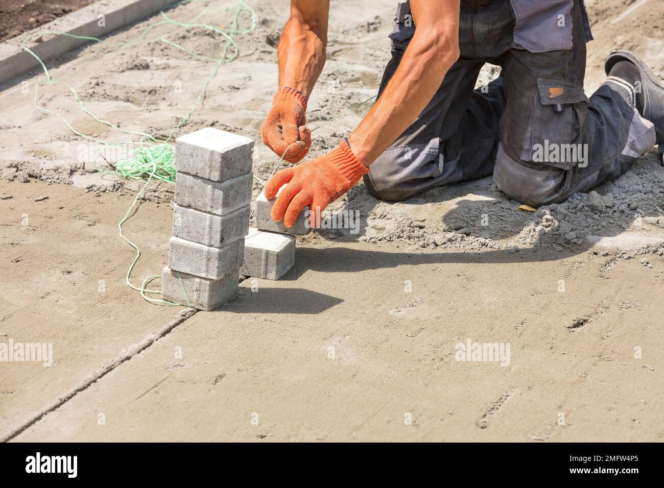 A worker installs nylon thread on paving slabs on a sand base for later ...