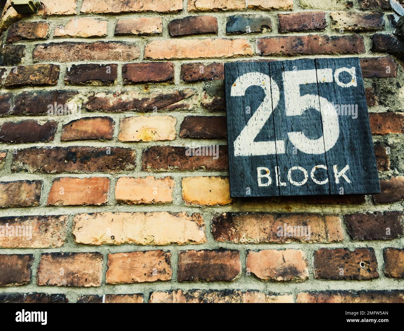 A wooden sign of 25 block on a brick wall in Auschwitz-Birkenau ...