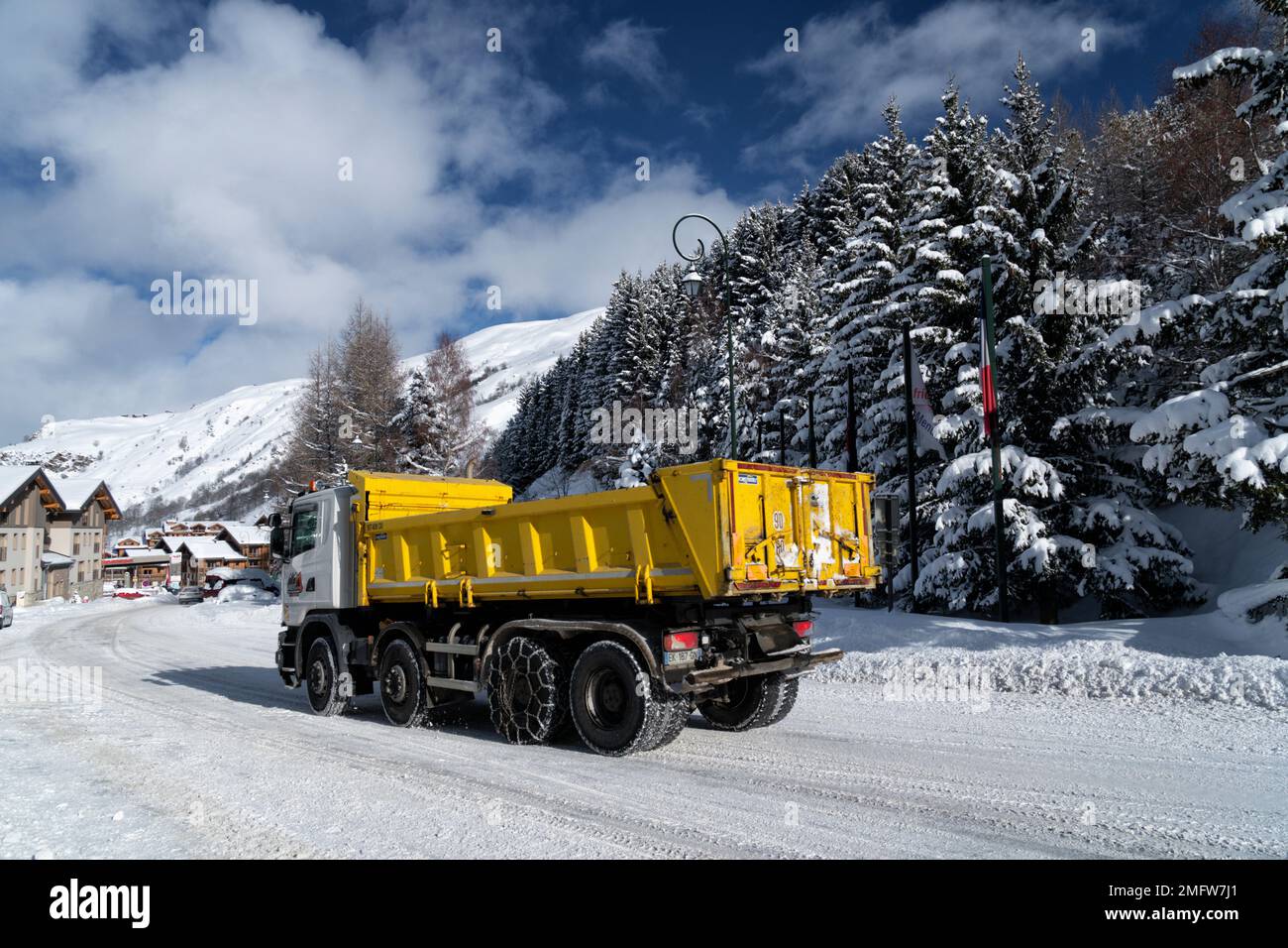 A bright yellow dumper truck clearing roads in the resort of Les ...