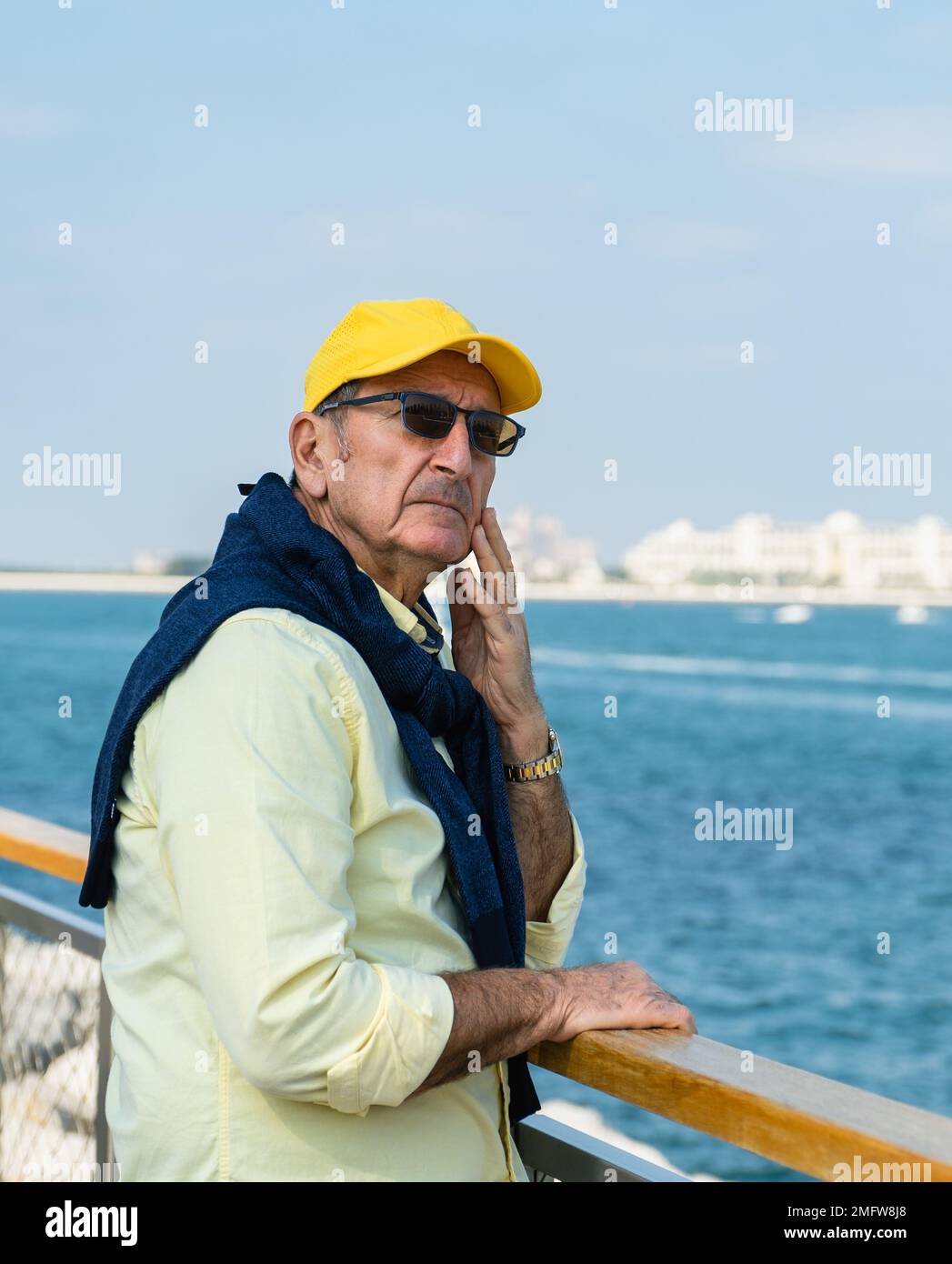 Senior man walking along a promenade alongside a marina Stock Photo - Alamy