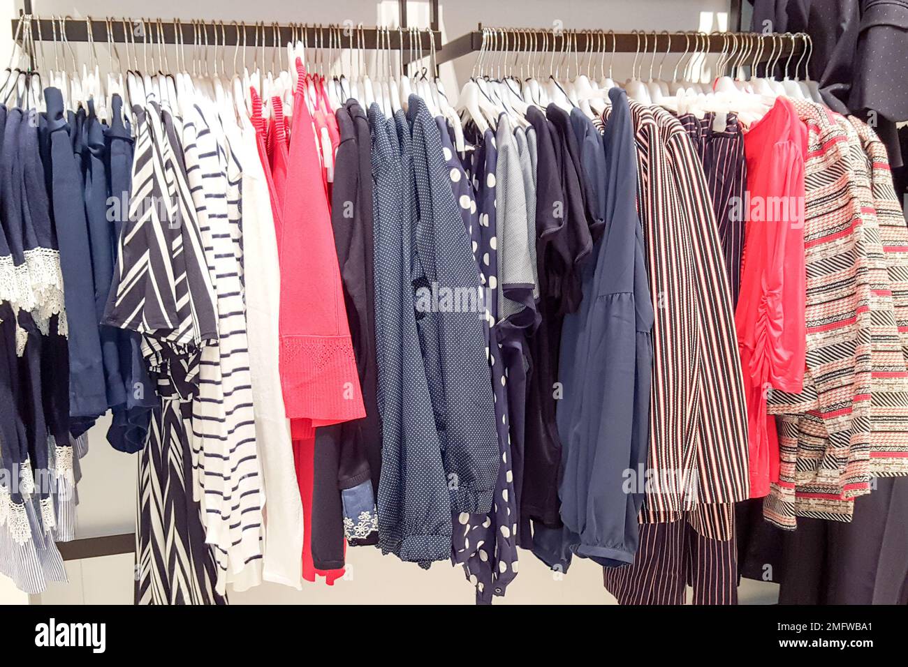 Clothes hanging on hangers in a clothing store retail shop Stock Photo ...