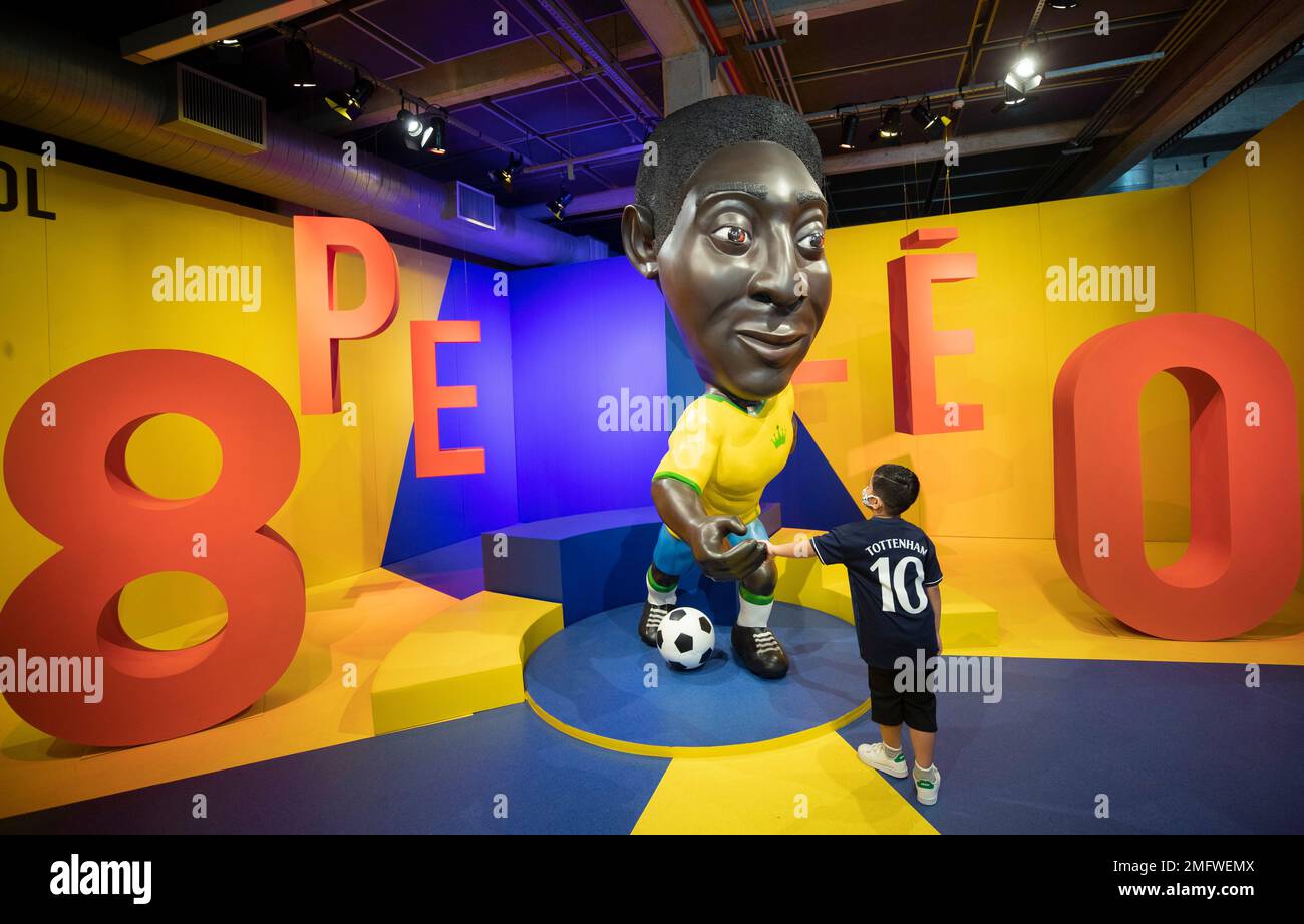 A boy touches the hand of a cartoon-style sculpture of soccer legend ...