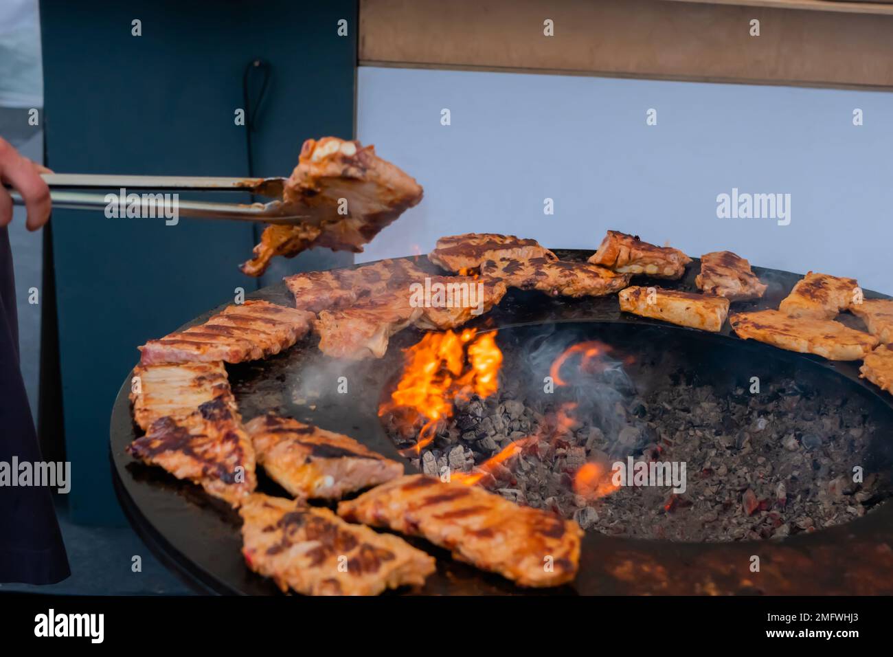 Chef with tongs grilling meat steaks on brazier with hot flame Stock ...
