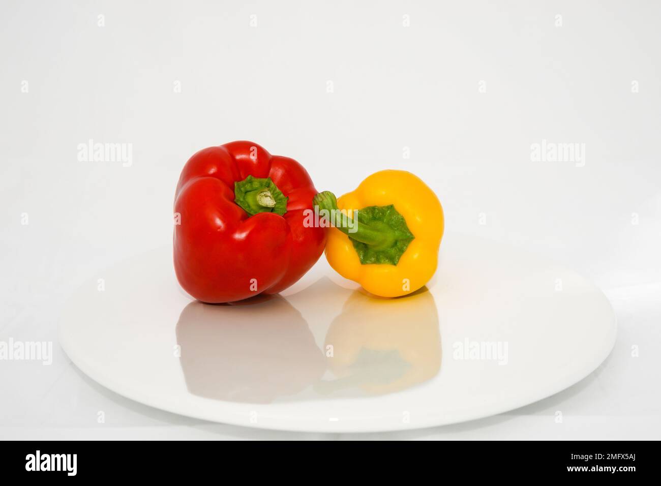 Two Capsicum fresh on white plate and background, red and yellow Stock ...