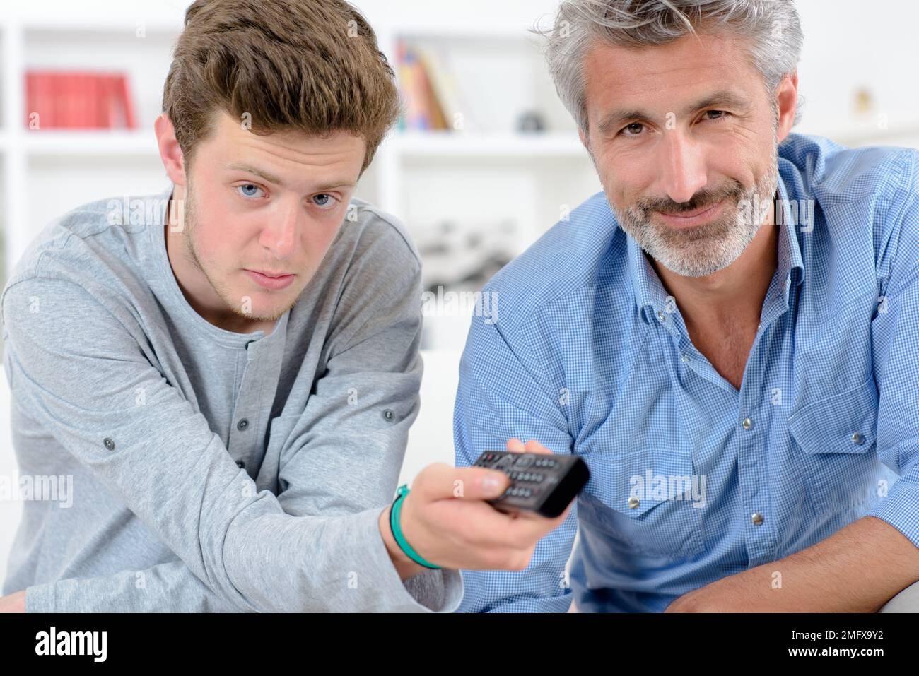 Portrait of adult and teenager holding remote control Stock Photo - Alamy