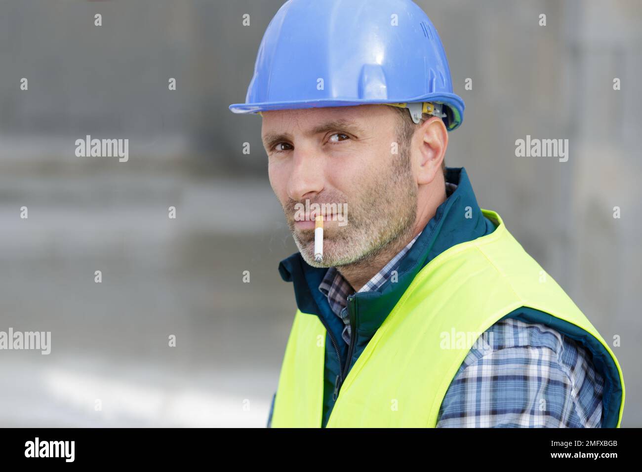 male worker wearing a refective vest smoking a cigarette Stock Photo ...