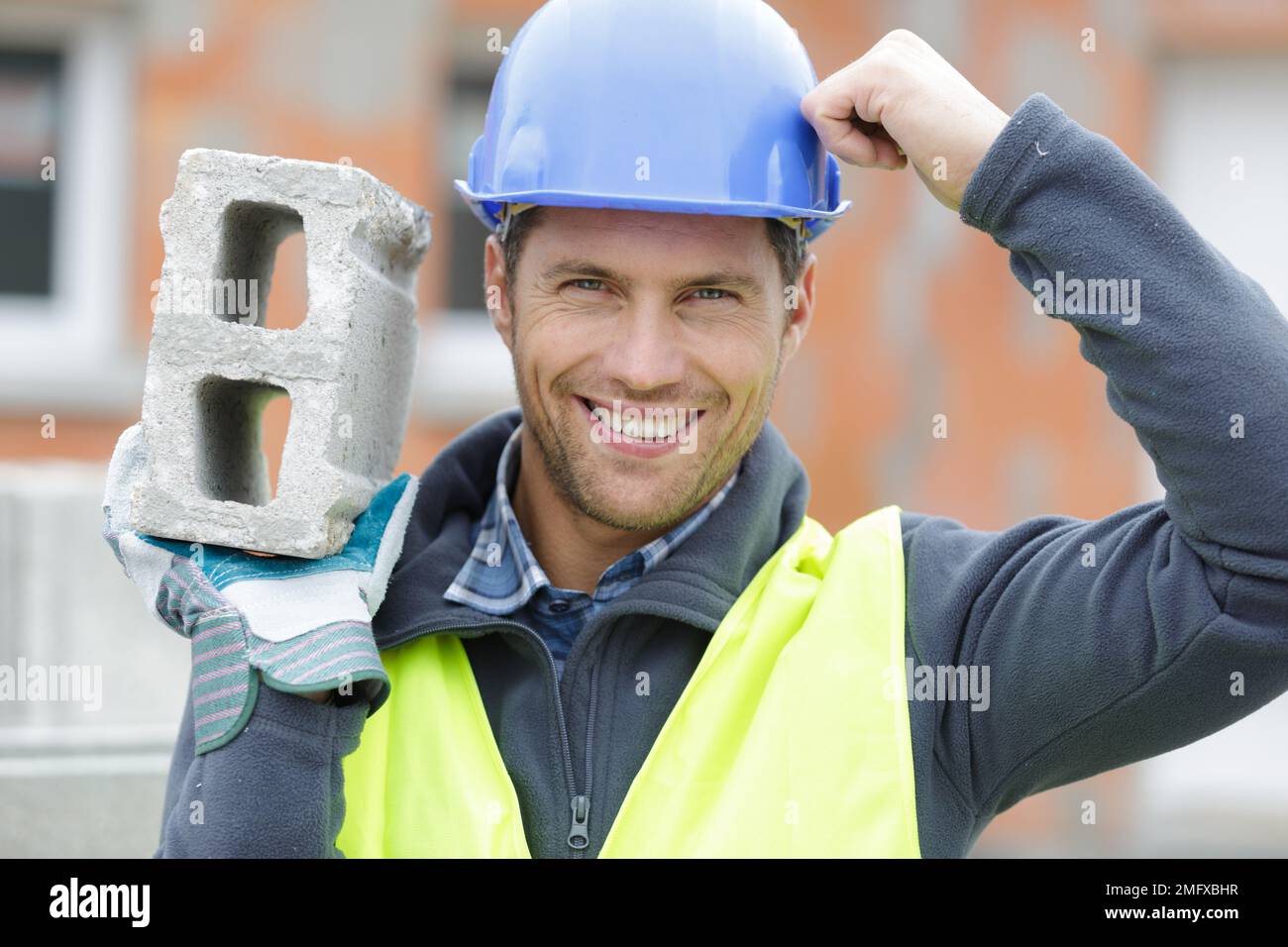 confident handsome builder helmet carrying a cement block Stock Photo ...