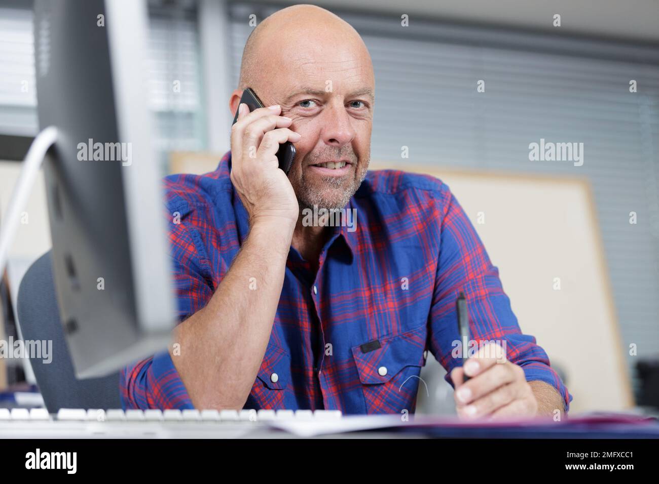 salesman sat at computer desk talking on smartphone Stock Photo - Alamy