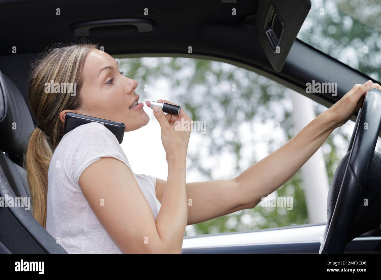 woman putting lipstick and talking on phone while driving Stock Photo ...