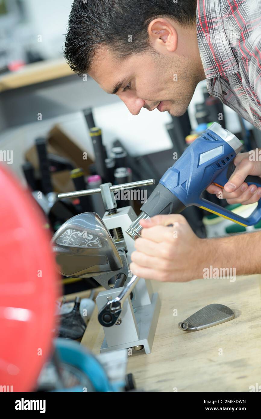 man using a heat gun to shape an object Stock Photo - Alamy