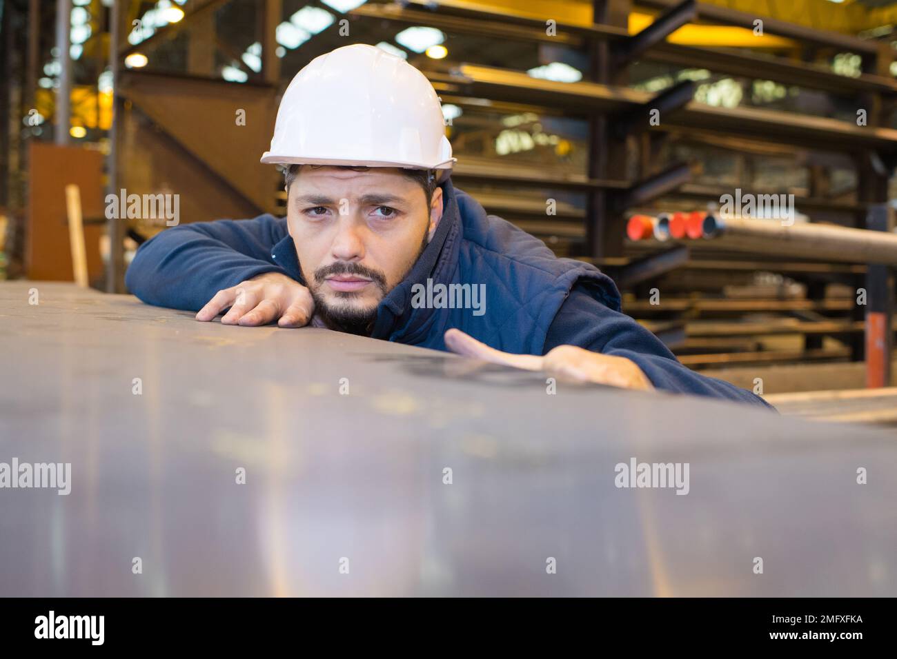 workman looking over the surface of sheet of metal Stock Photo - Alamy