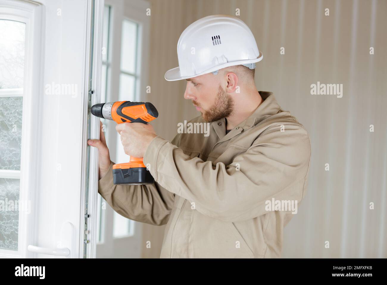 male contractor using drill on window Stock Photo - Alamy