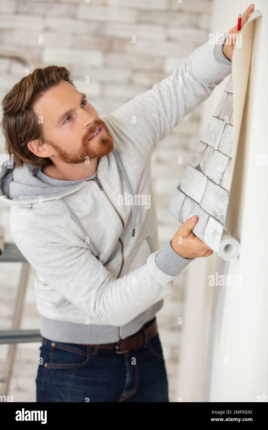 man holding wallpaper against a wall for visual effect Stock Photo - Alamy