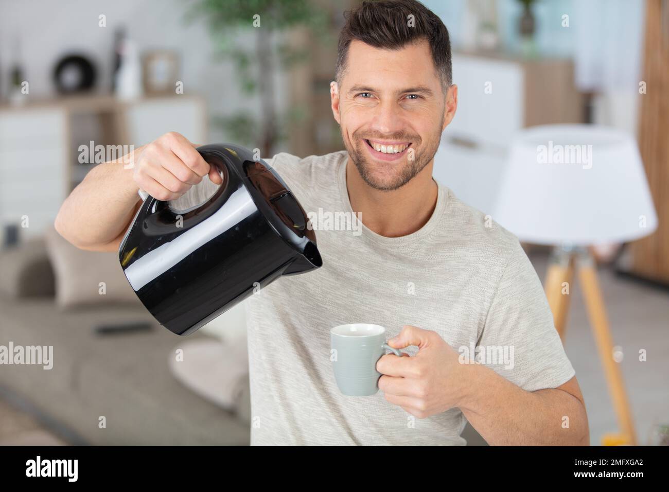 man pouring water from electric kettle Stock Photo - Alamy