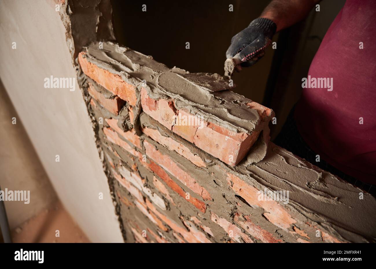Close up of man hand in work glove laying brickwork in building under ...