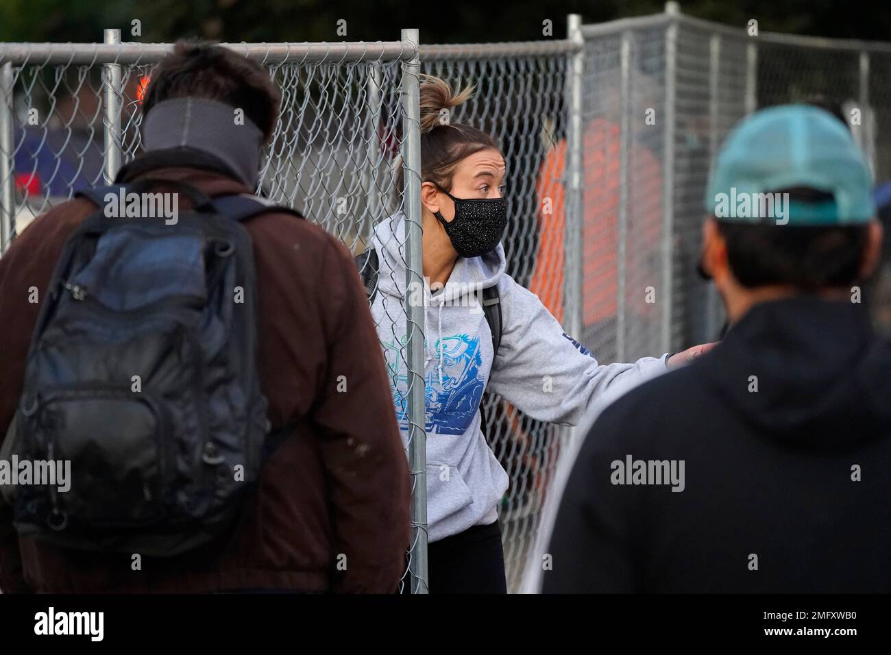 A woman closes the gate to a homeless encampment during a sweep of the ...