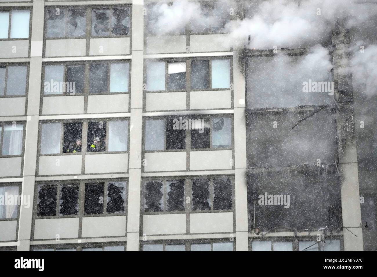 Chicago firefighters look out windows a few floors below where flames ...